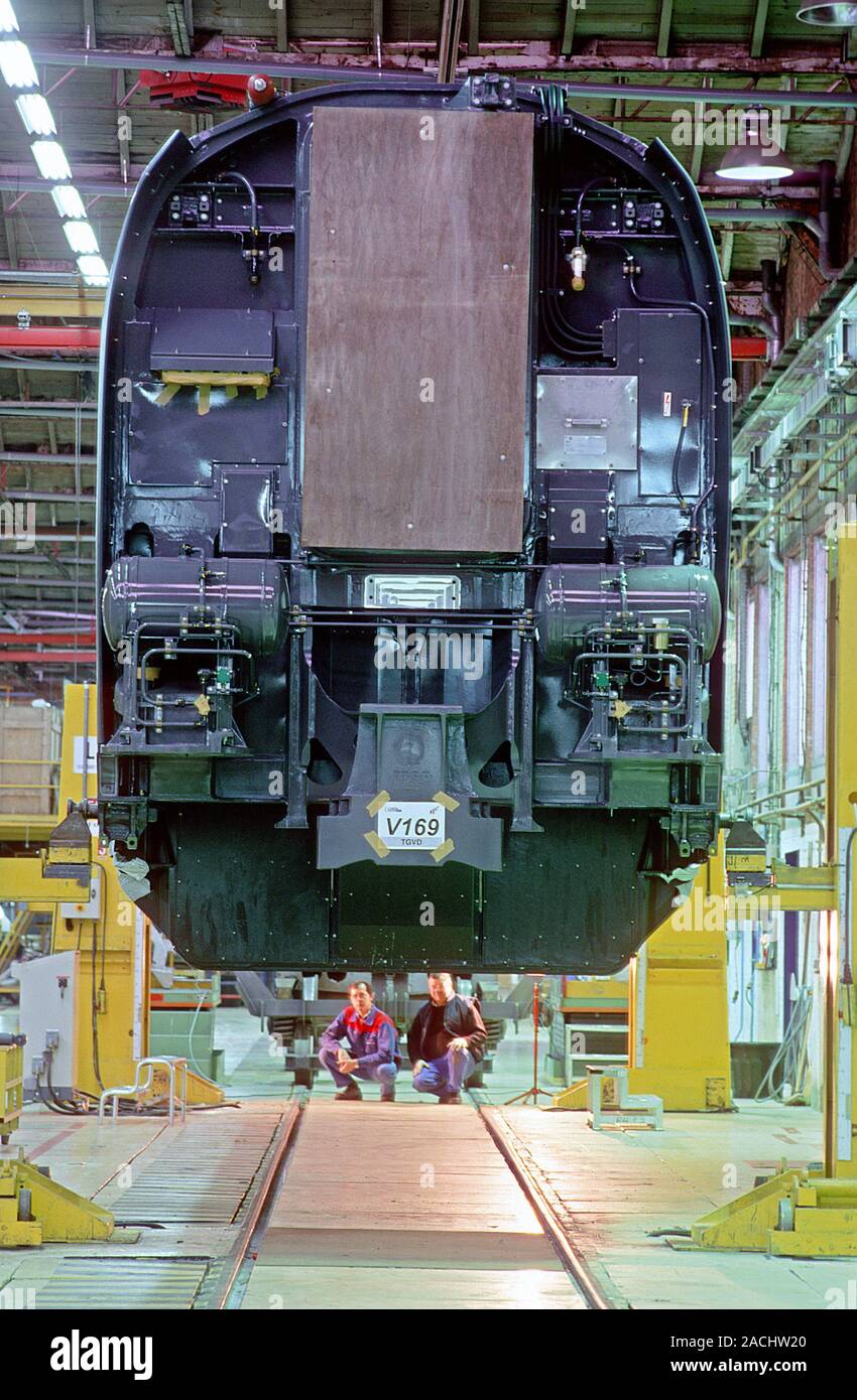 High-speed train production. Workers preparing to fit the wheels to a a ...