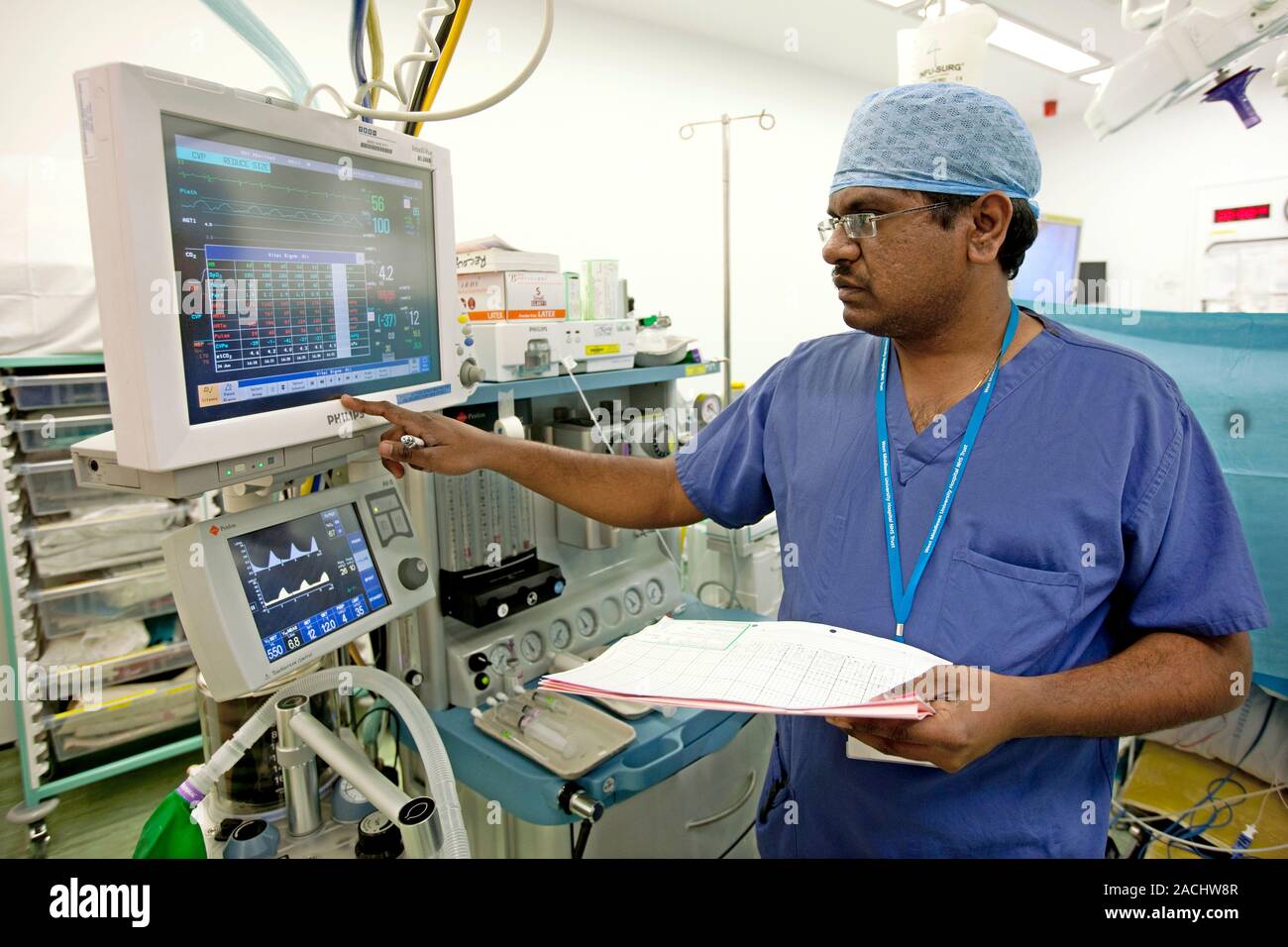 Vital signs monitor. Anaesthetist checking the screen that shows a ...