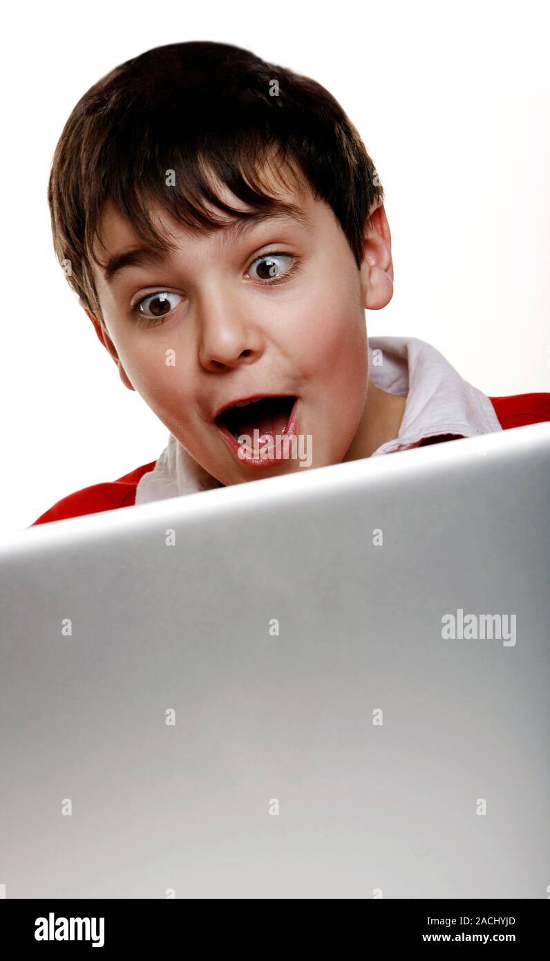 Boy using a laptop computer, with his mouth and eyes wide open in surprise and amazement Stock ...