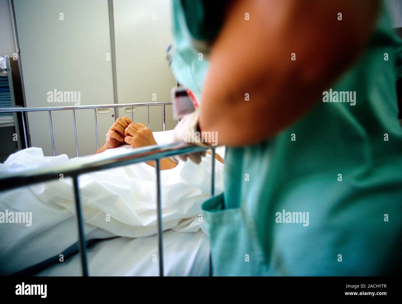 Nurse with coma patient, in a bed on a hospital ward. This patient is ...