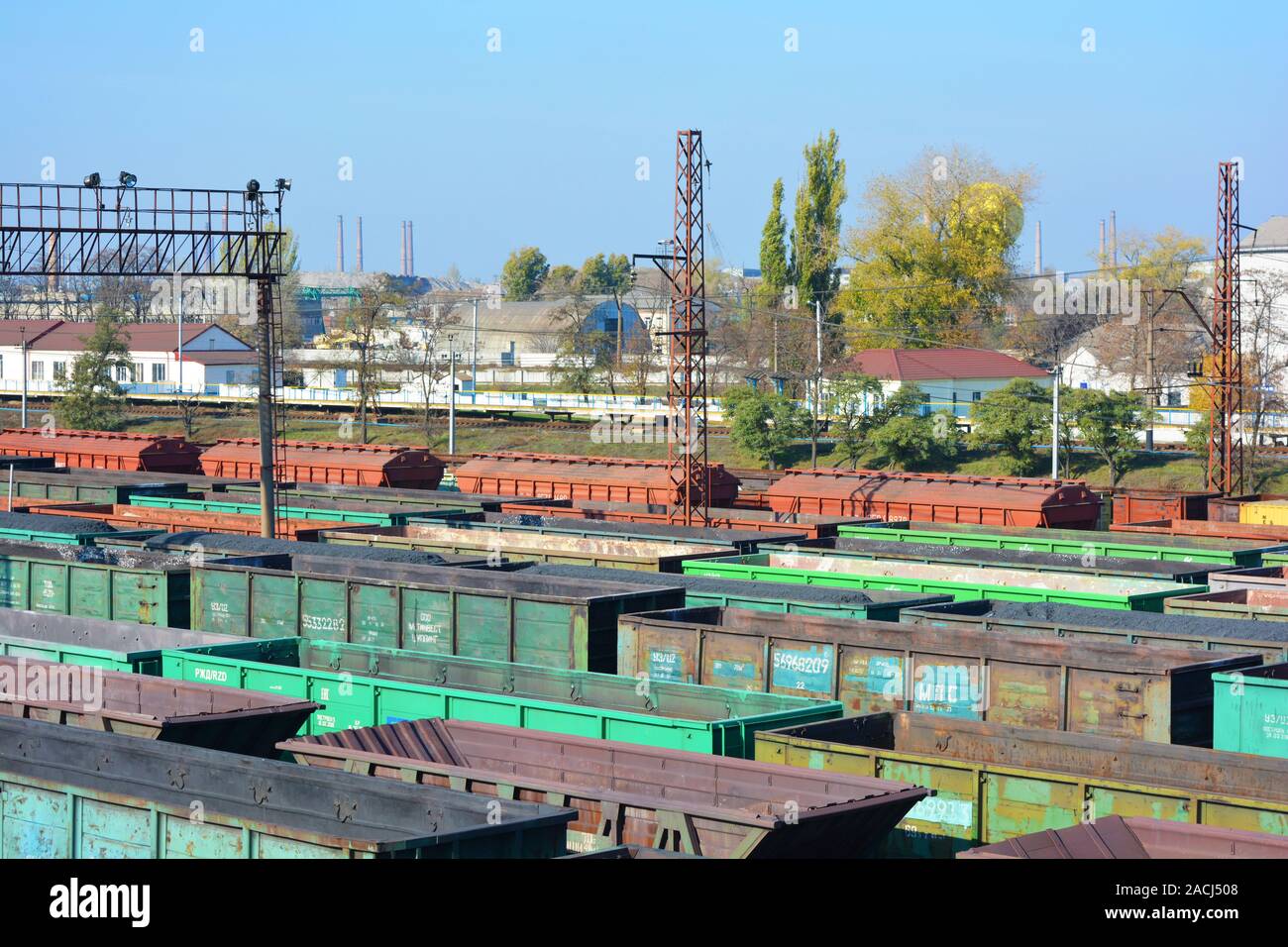 A railroad junction with iron slats and trains loaded with wagons lit ...