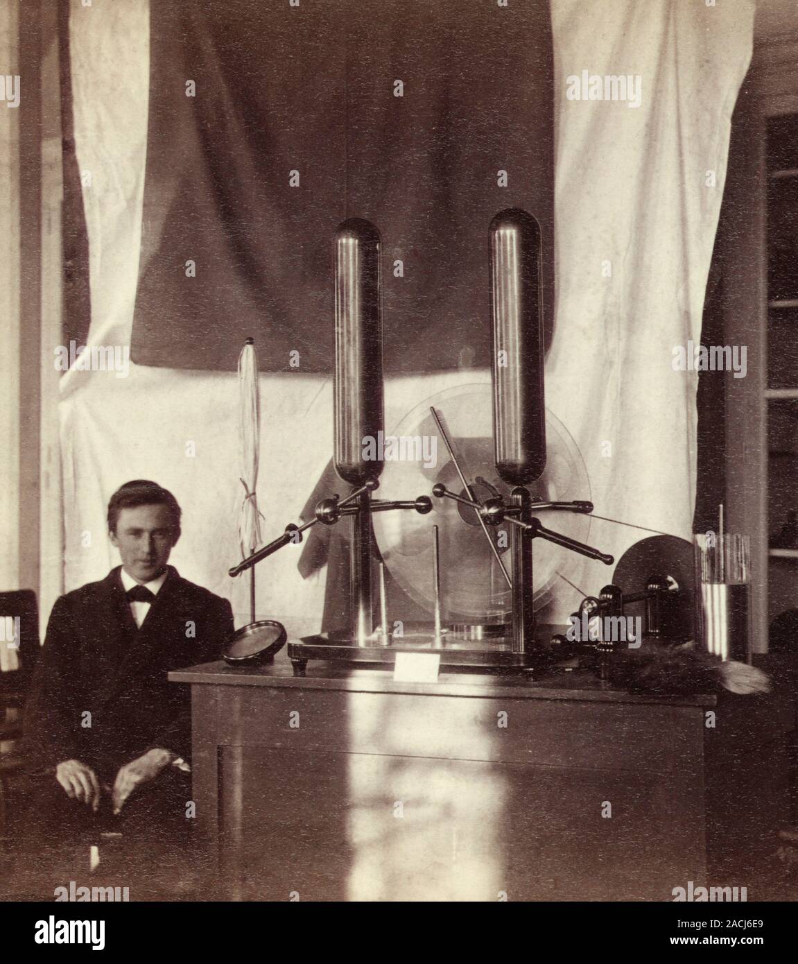 19th Century electrostatic generator. Historical image of a man seated ...