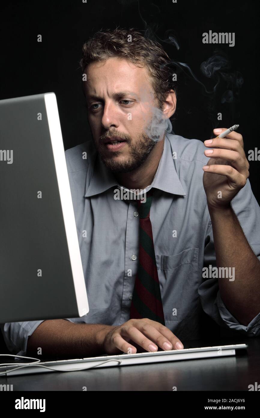 Work stress. Man smoking to help with stress while working at a ...