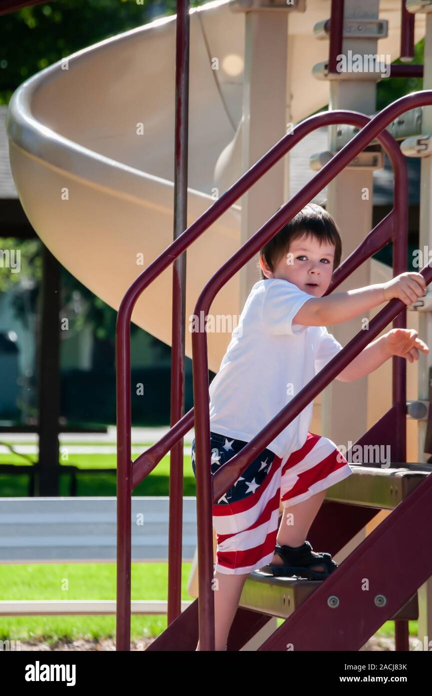 Little boy playing on playground equipment at the city park on a warm ...