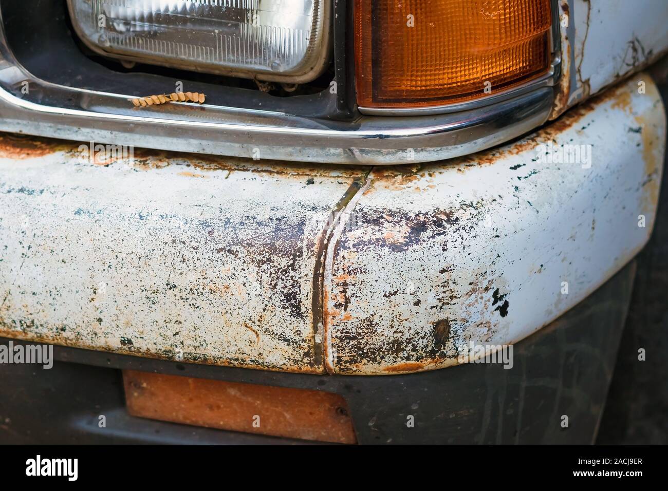 Colse up to decay and rust on the front bumper of an old white truck ...
