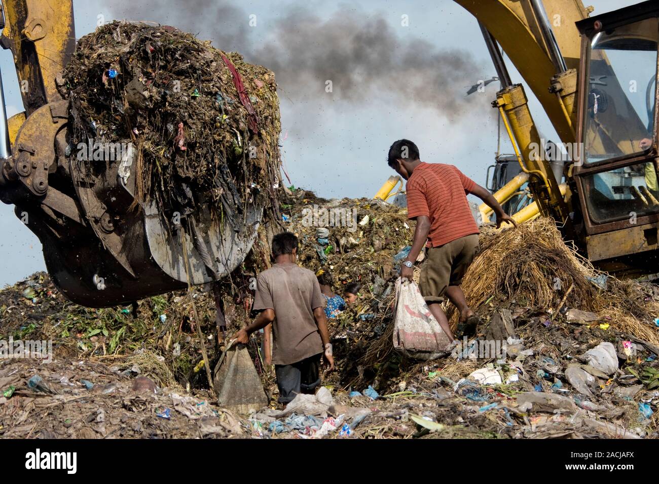Rubbish dump workers. Children collecting recyclable items on rubbish ...