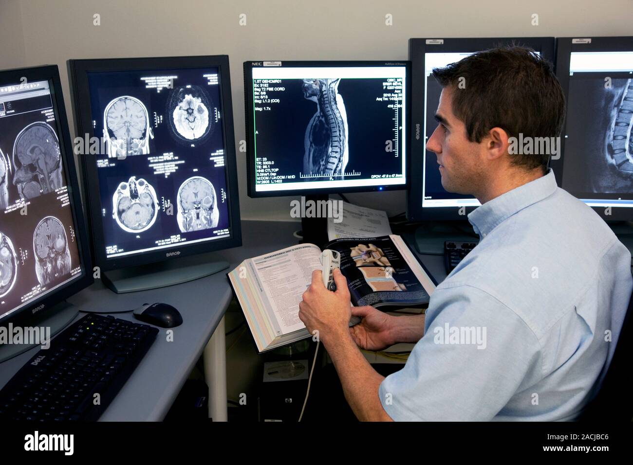 Brain and spine CT scanning. Radiographer using a remote control to ...