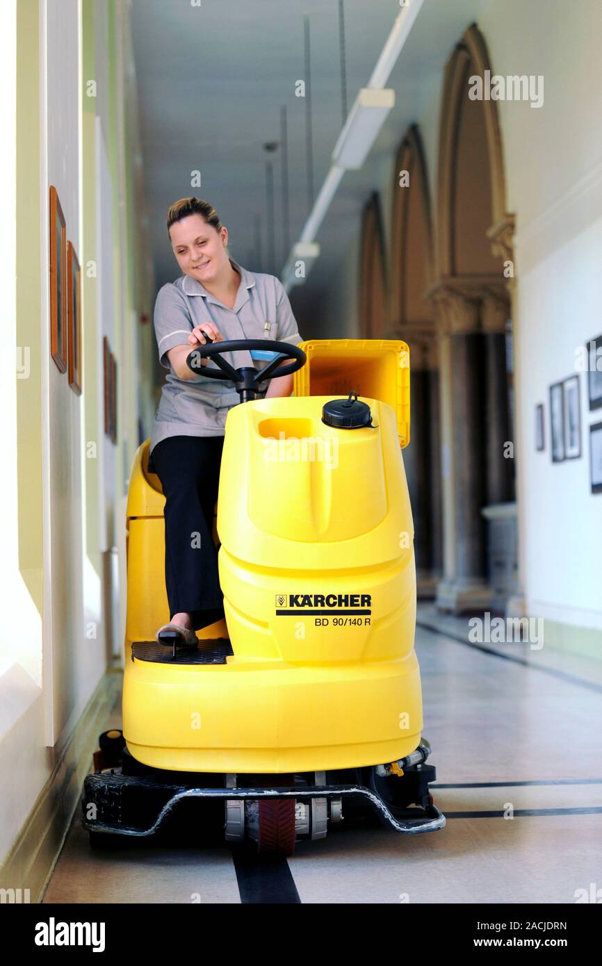 Hospital cleaning. Cleaner using a ride-on scrubber drier to clean a ...