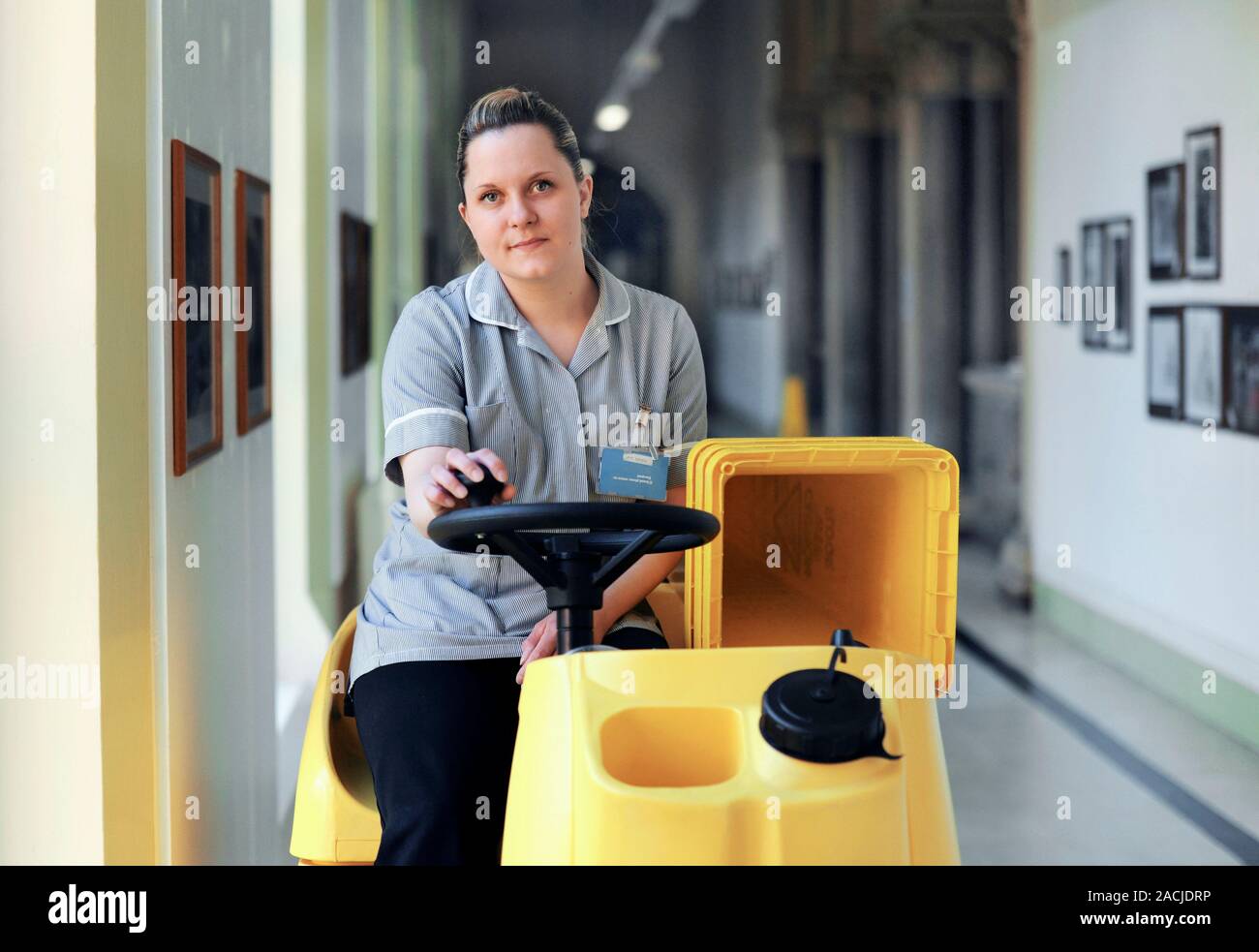 Hospital cleaning. Cleaner using a ride-on scrubber drier to clean a ...