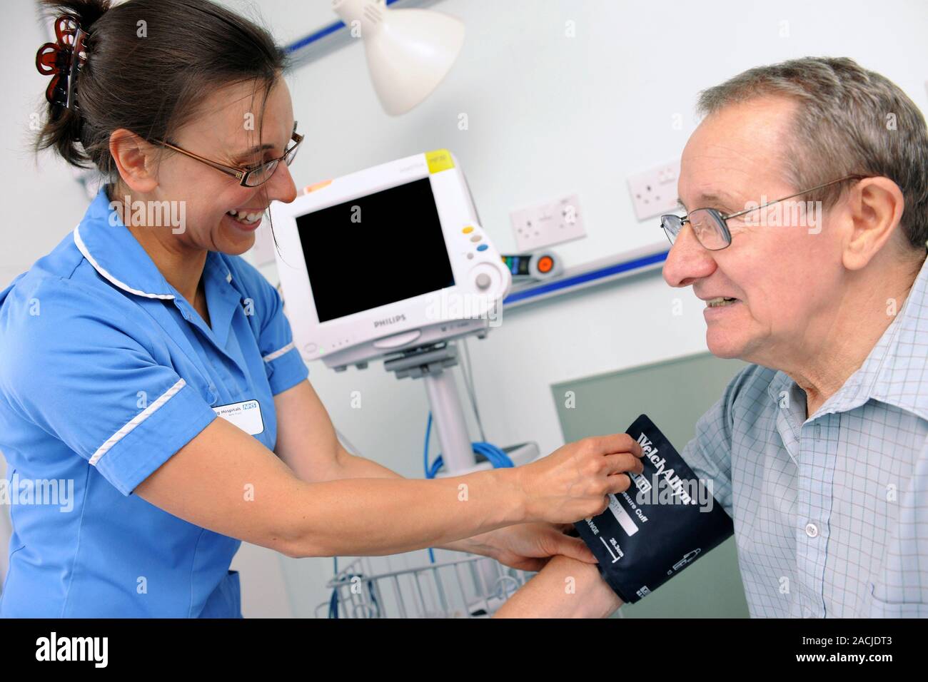 Taking blood pressure. Nurse fitting an inflatable cuff around a man's ...