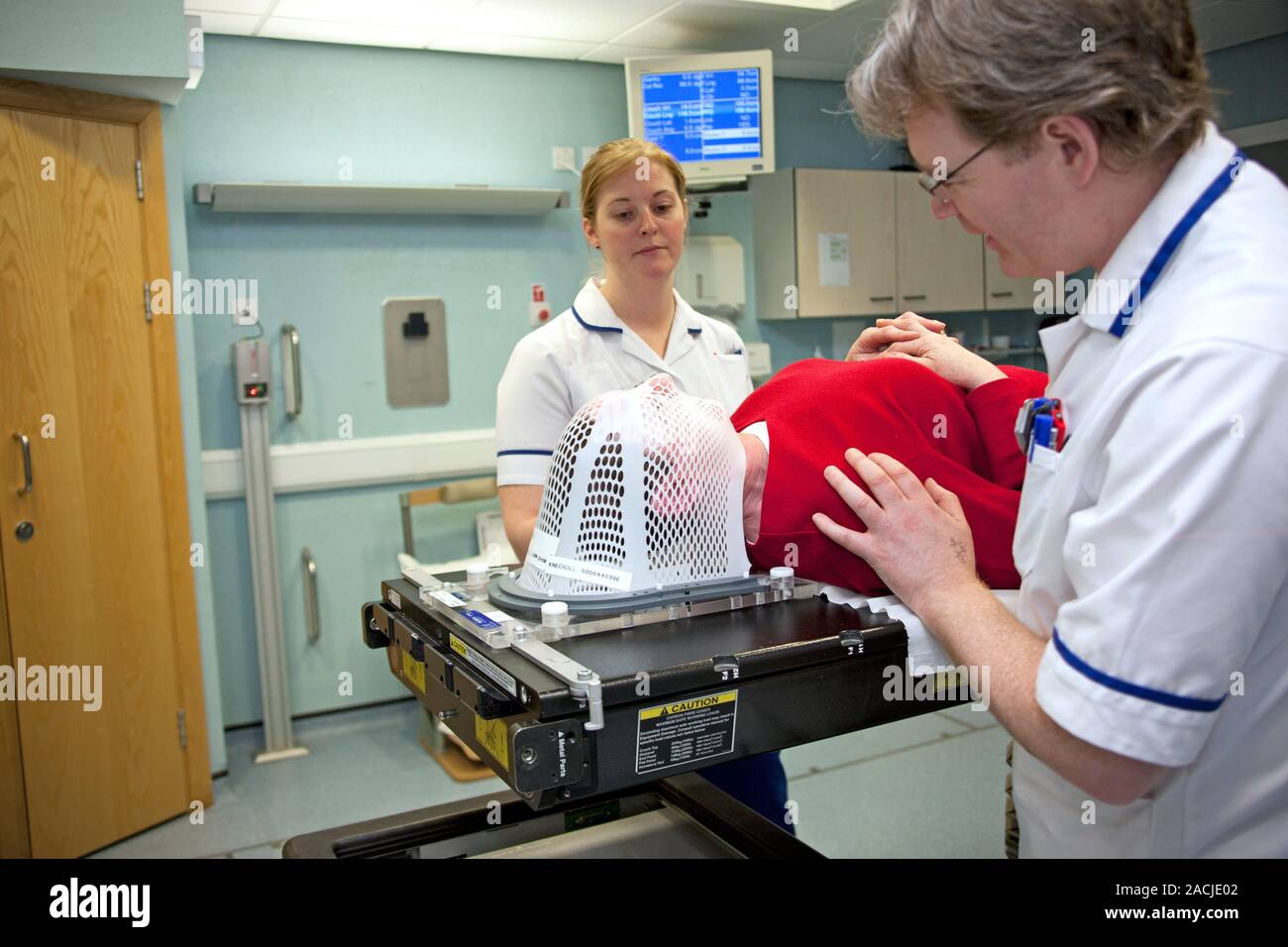 Radiotherapy simulator. Patient being lined up on an X-ray machine used ...