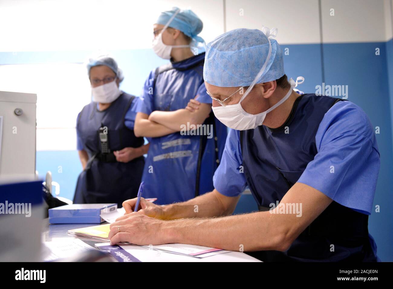 Surgical staff. Surgeon writing up notes while other surgical staff ...