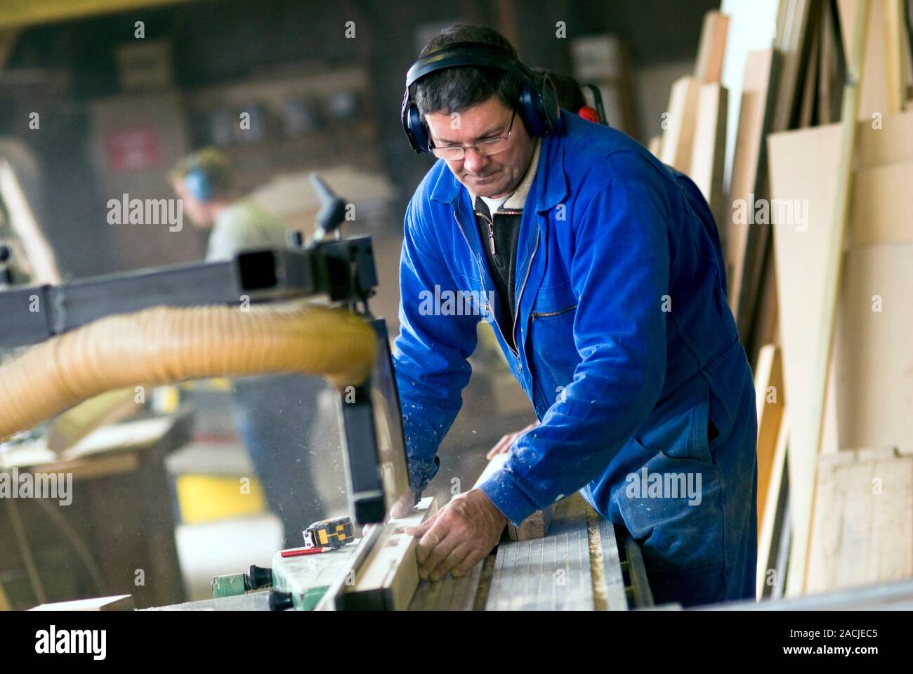 Timber frame house construction. Joiner in a workshop making sections ...