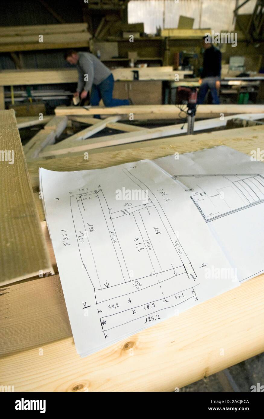 Timber frame house construction. Joiners in a workshop making sections ...