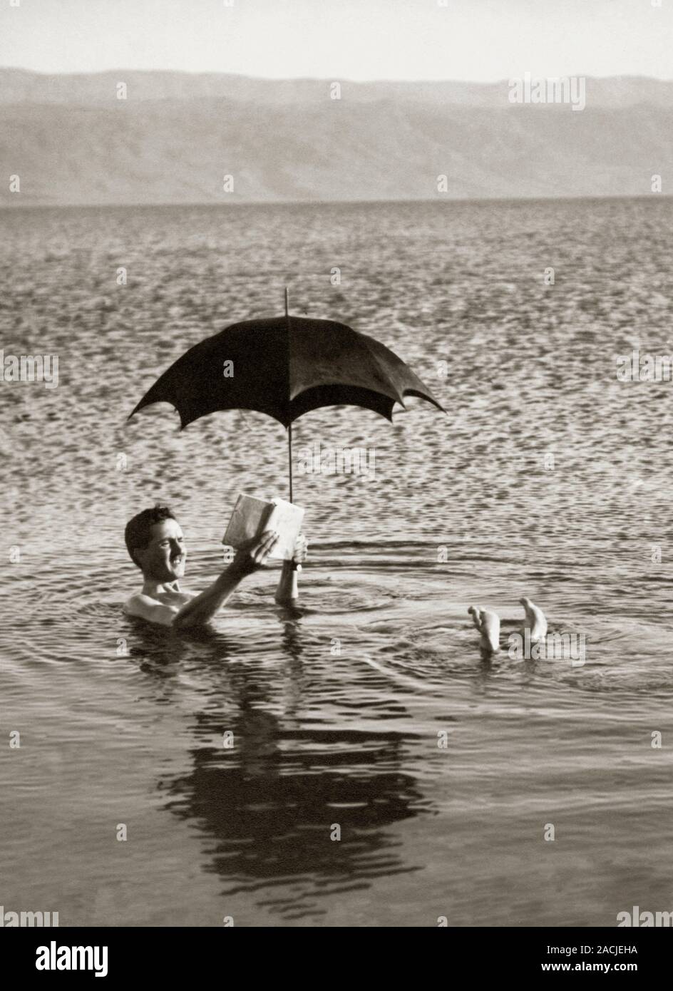 Man floating in the Dead Sea. Early 20th Century image of a man reading ...