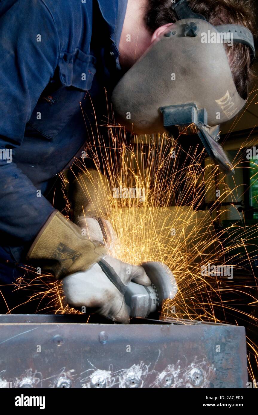 Metal working. Metalworker using an angle grinder in an engineering ...