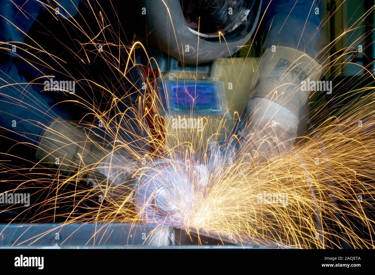 Metal working. Metalworker using an angle grinder in an engineering ...