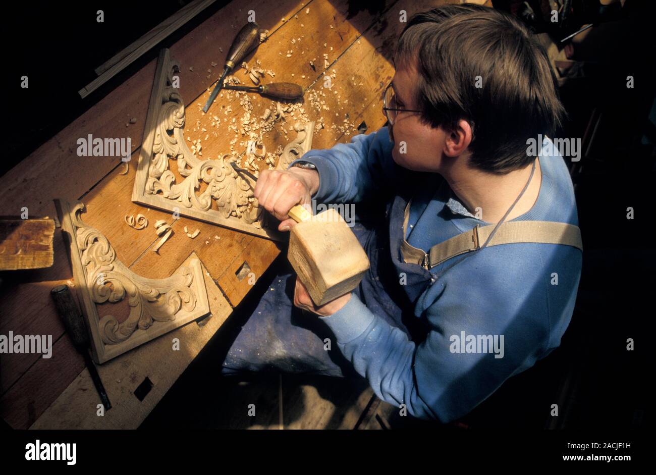 Organ building. Organ builder shaping the ornate wood carvings that ...