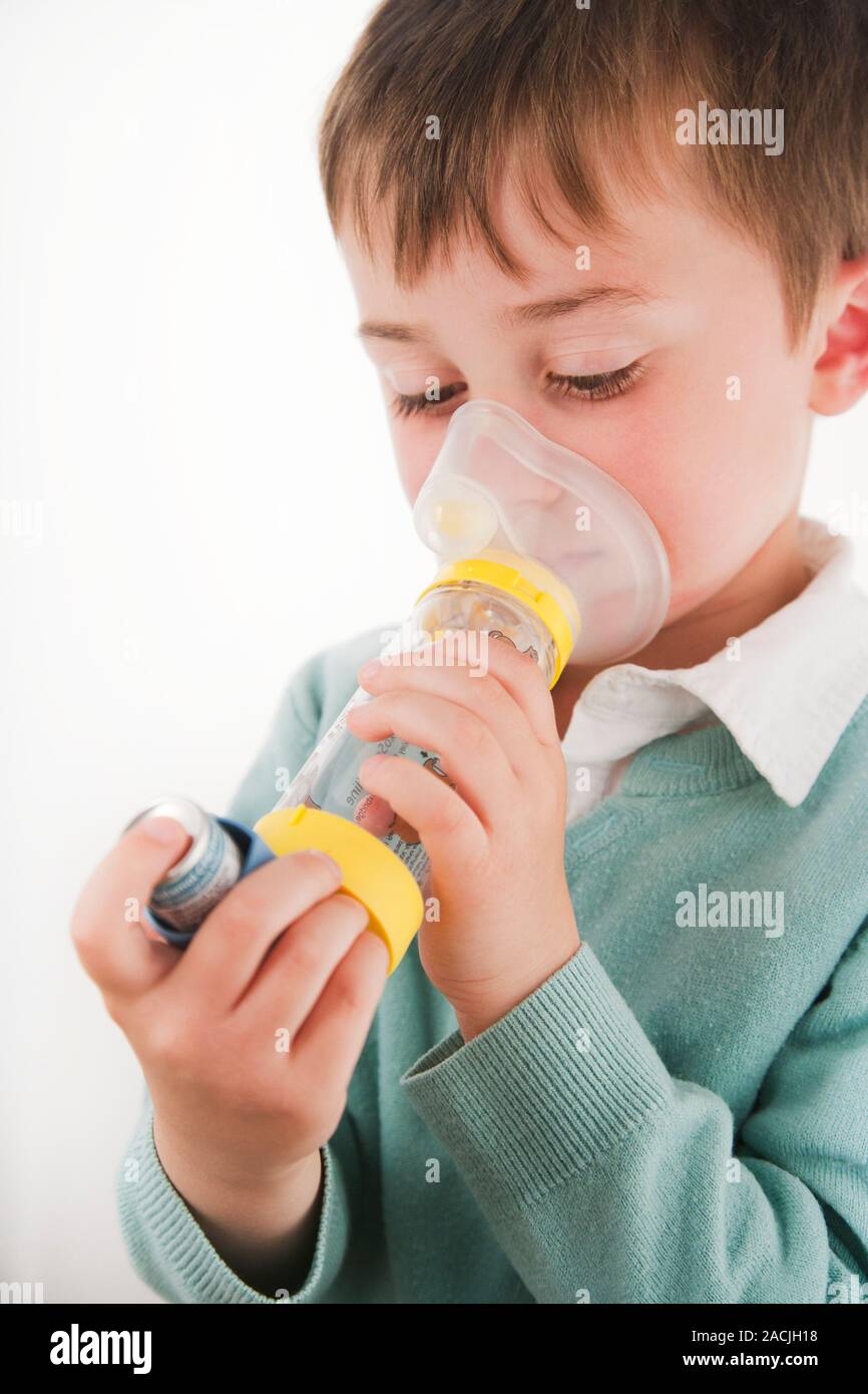 Boy using an asthma spacer with an asthma inhaler. He is five years old ...