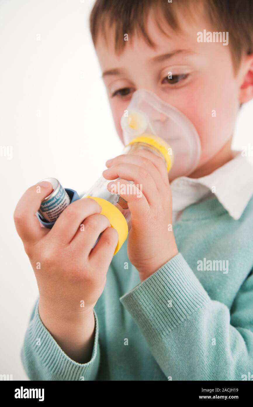 Boy using an asthma spacer with an asthma inhaler. He is five years old ...