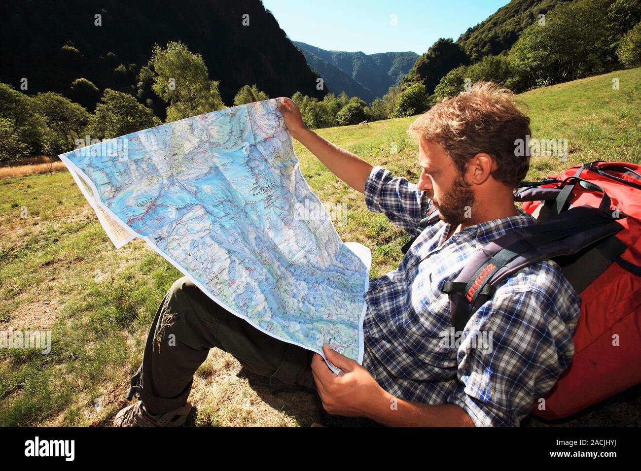 Hiking. Hiker reading a map whilst resting in the sun on a grass ...