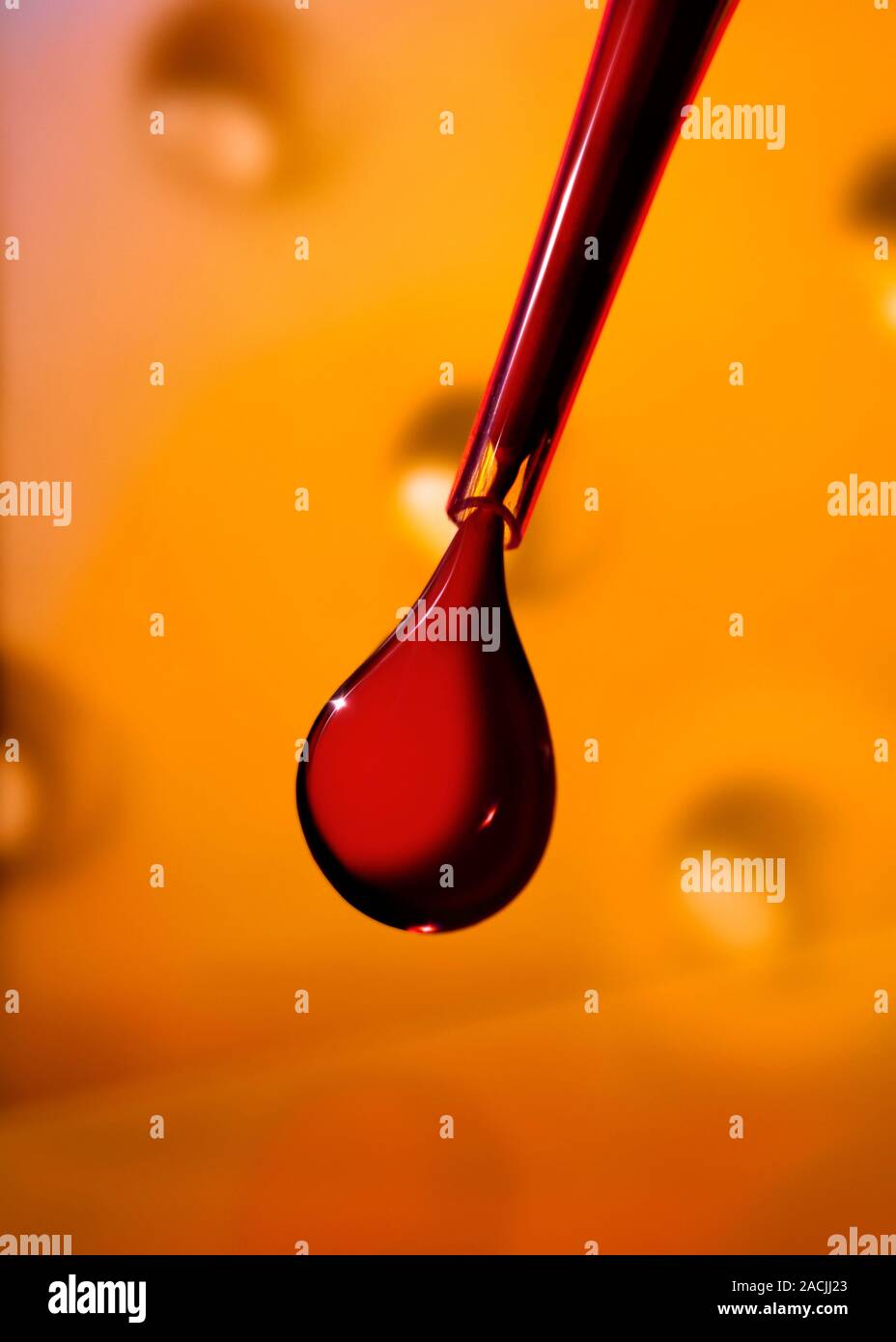 Pipette and drop of blood. Close-up of a drop of blood forming at the ...