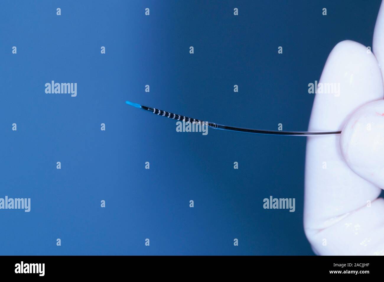 Coronary angioplasty surgery. Surgeon holding a stent (wire mesh tube ...