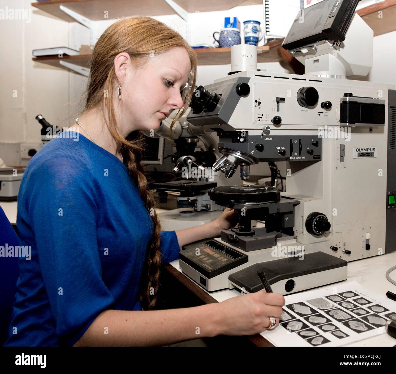 Rock research. Researcher using a petrographic microscope to study the ...