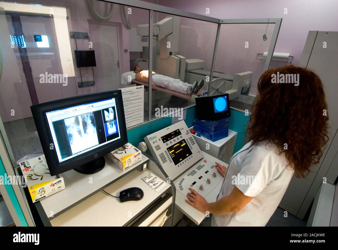 Chest X-ray. Radiographer operating an X-ray machine to take an X-ray ...