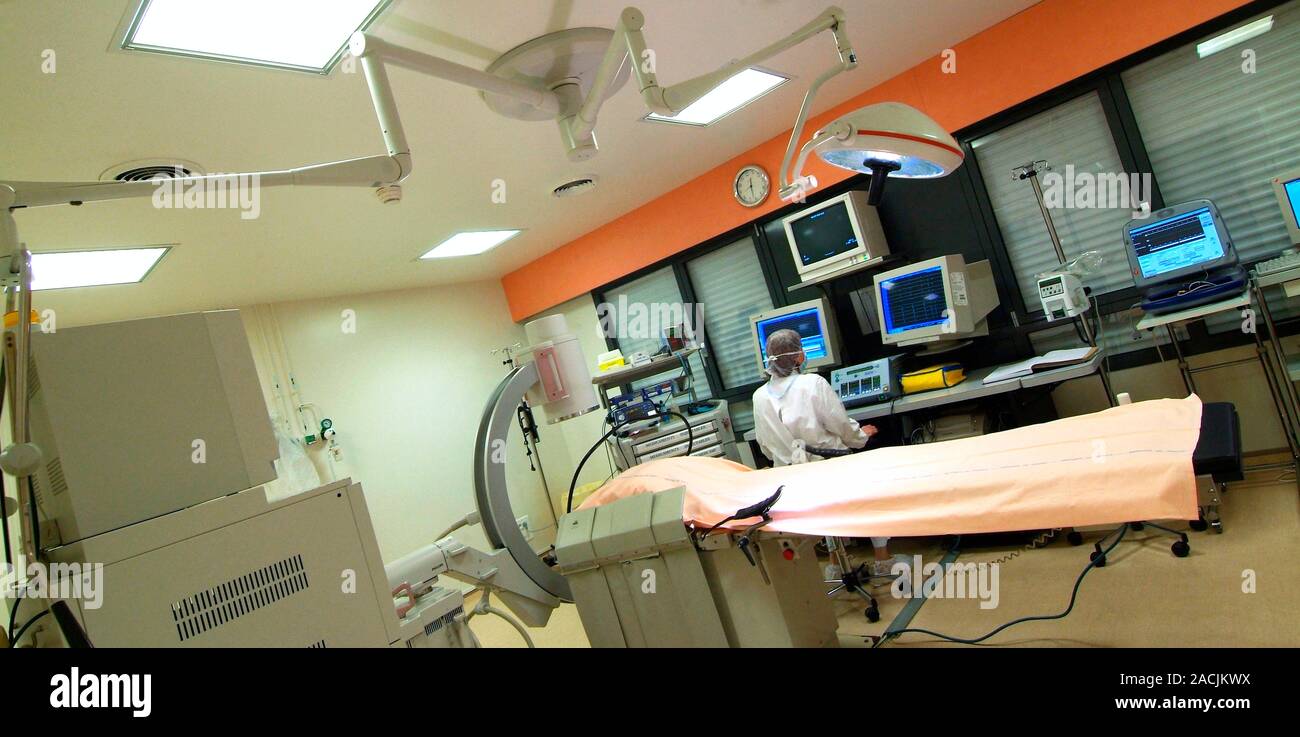 Angiography. Medical staff member checking recordings of the electrical ...
