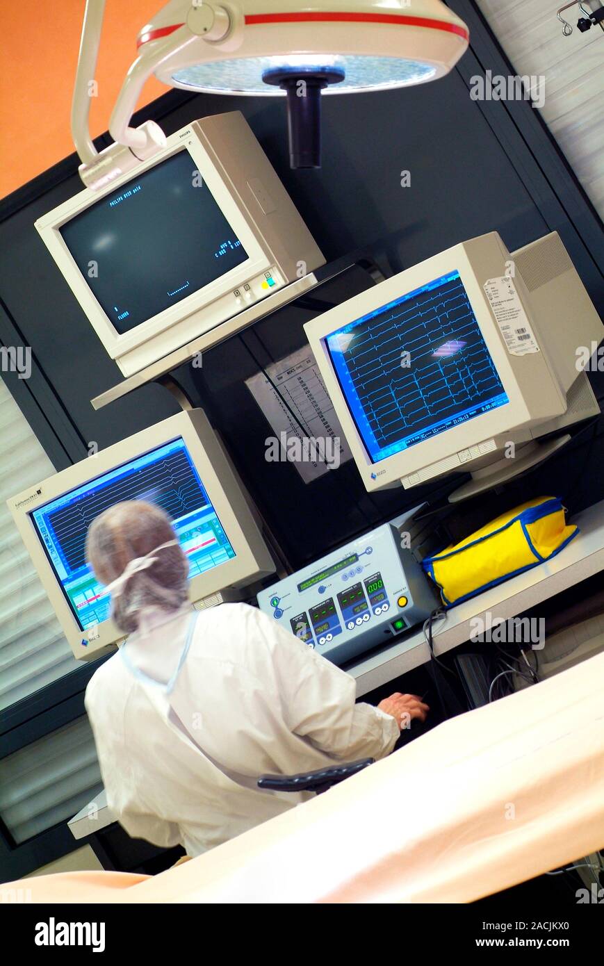 Angiography. Medical staff member checking recordings of the electrical ...