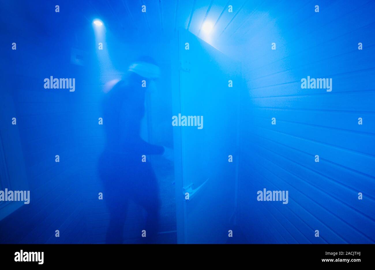 Cryogenic chamber therapy. Patient stepping into a cryotherapy chamber ...