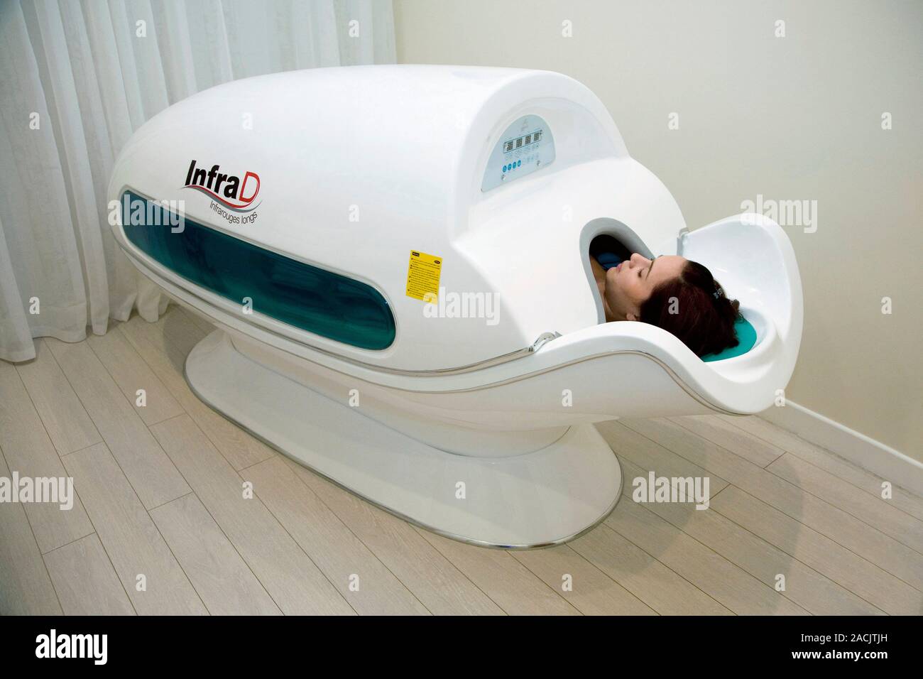 Infrared therapy. Woman in a machine that uses infrared radiation to ...