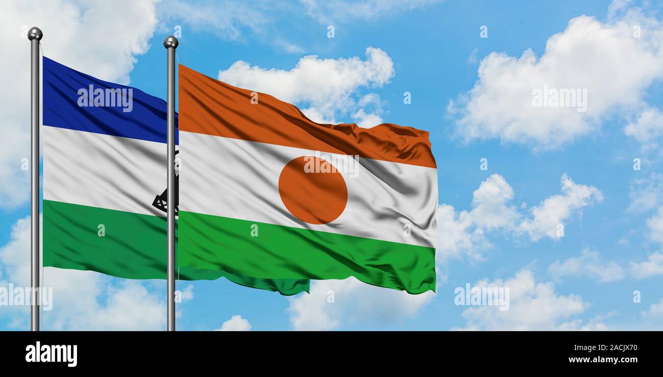 Lesotho and Niger flag waving in the wind against white cloudy blue sky ...