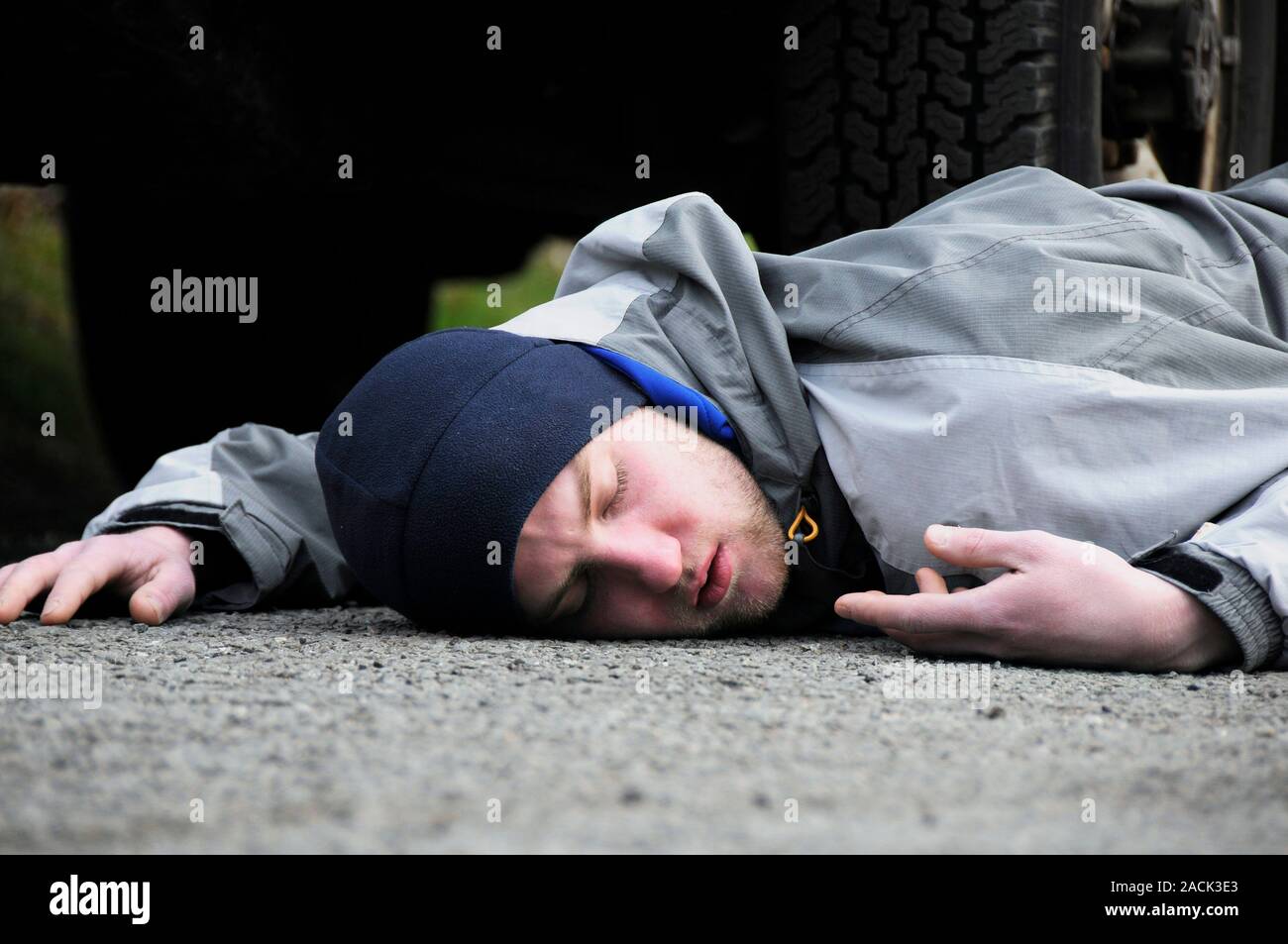 Road traffic accident. Unconscious man lying hurt in the road next to ...