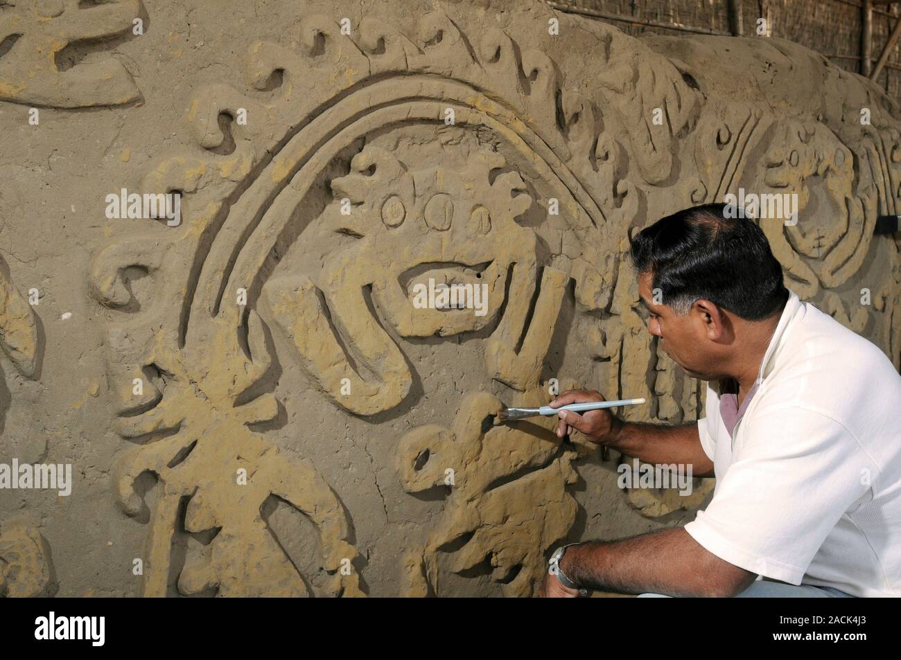 Ancient Peruvian carvings. Archaeologist cleaning bas-relief carvings ...