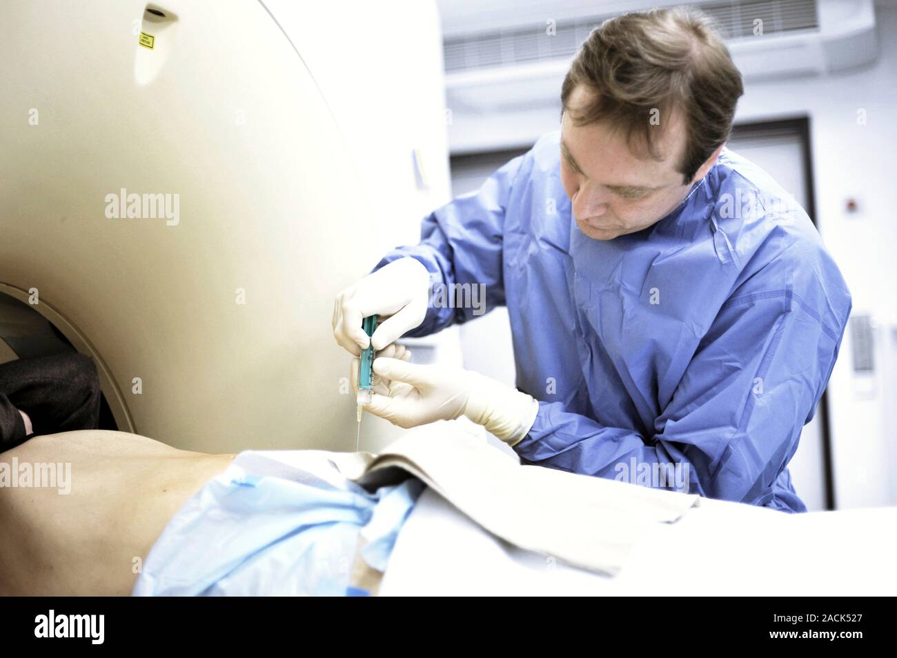 CT scan. Radiologist injecting a patient with contrast medium prior to ...