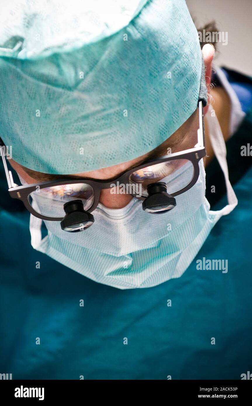 Surgeon wearing optical loupes to magnify his vision during surgery ...