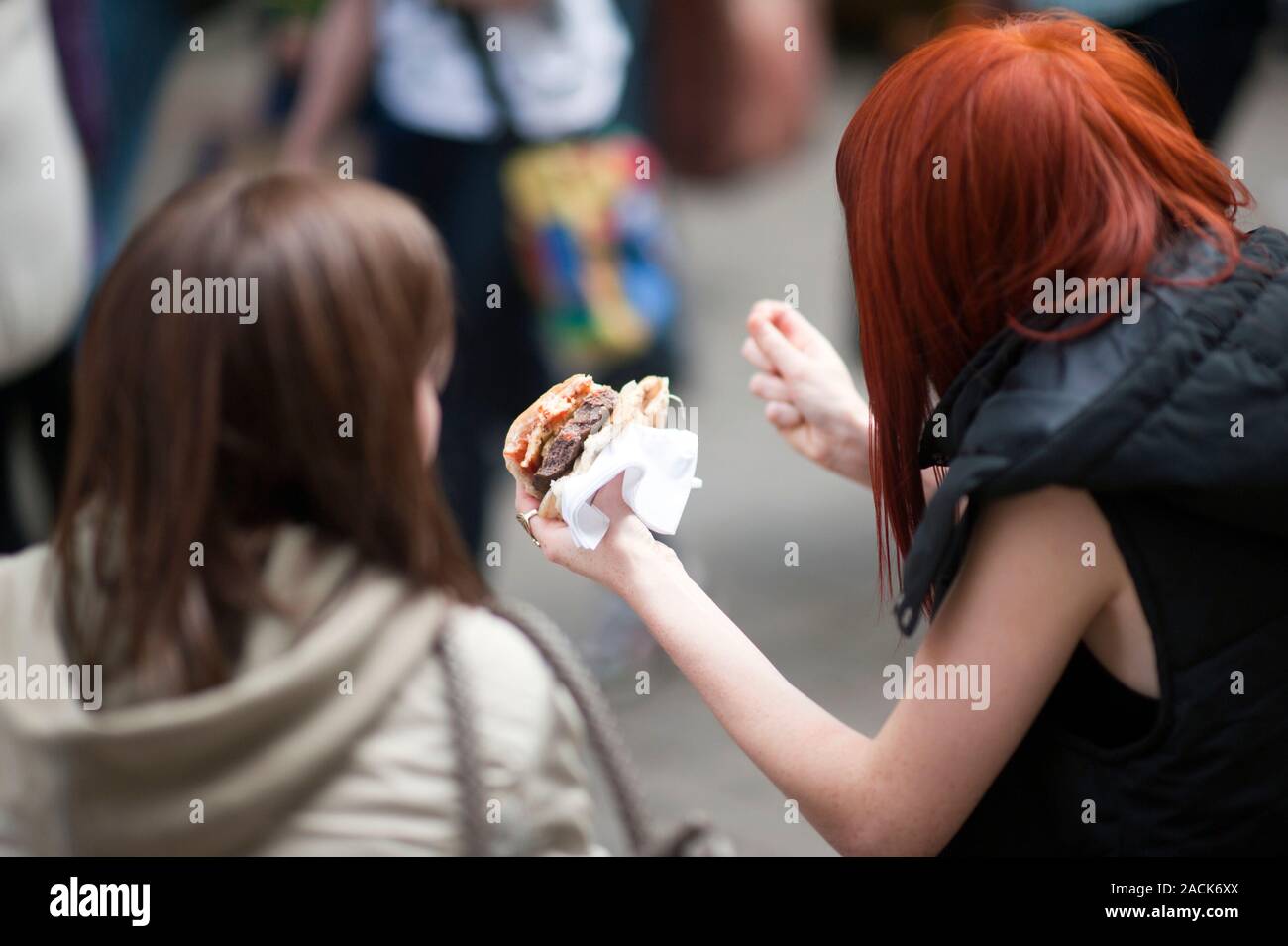 Teenager eating fast food. Teenage girl eating a beefburger in a ...