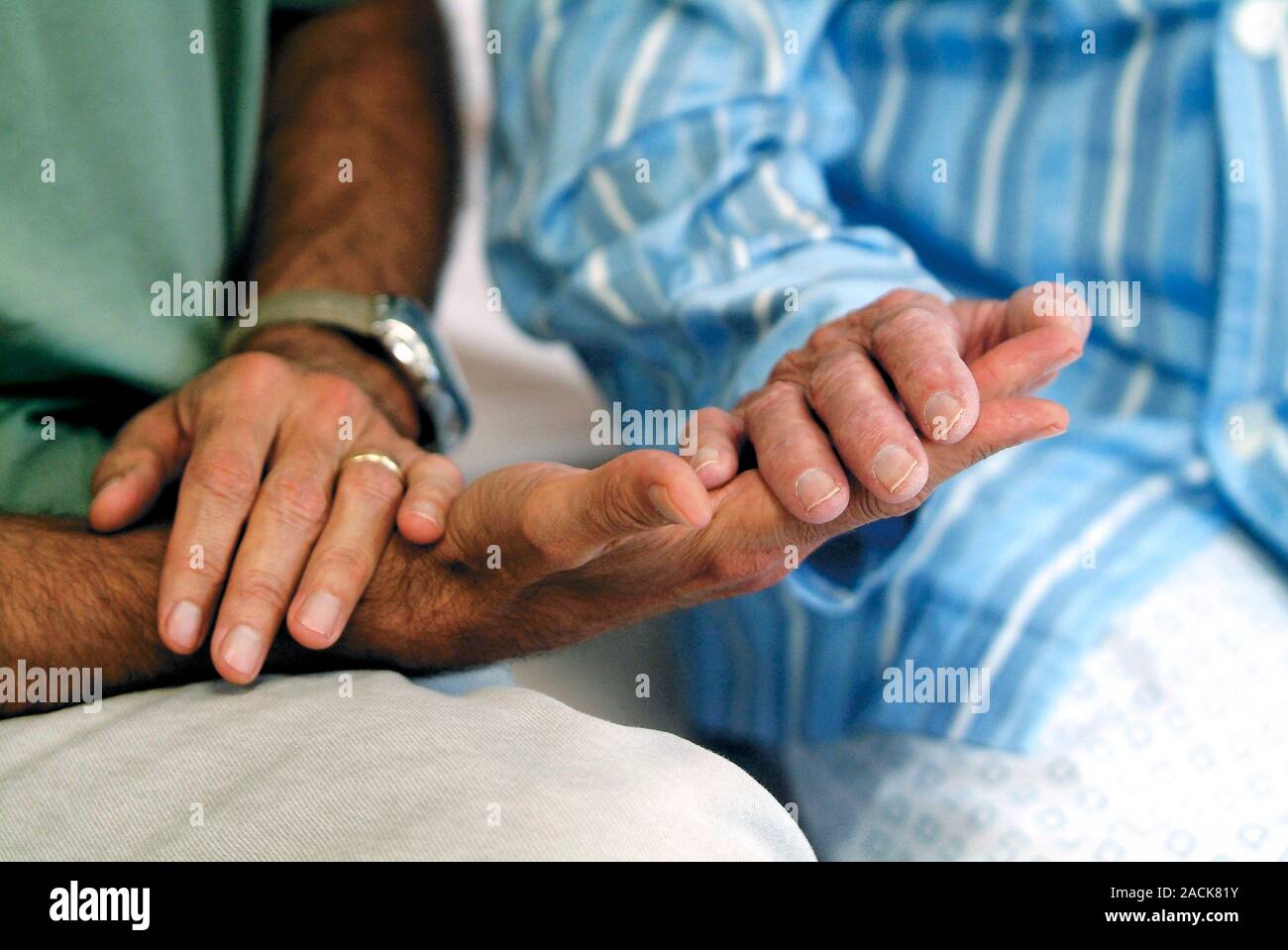 Geriatric care. Carer holding an elderly person's hand on the geriatric ...