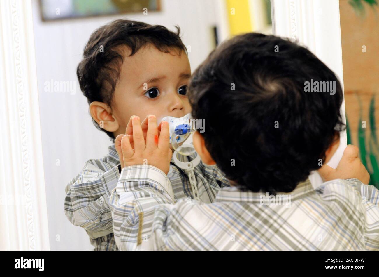 Child development research. Child in front of a mirror. The child has a ...
