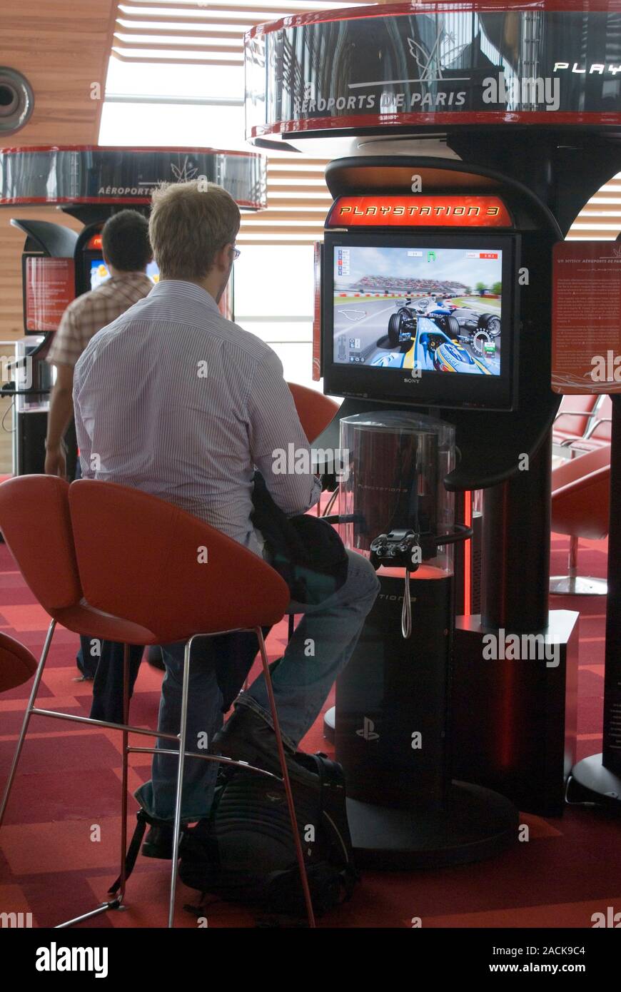 Man at Playstation 3 console in departure lounge at Terminal 2E, Paris ...