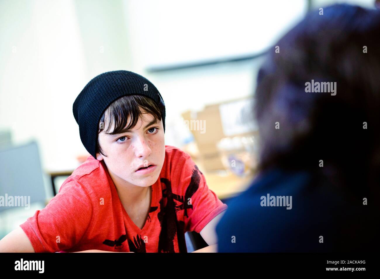 Young boy looking angrily at a teacher in a classroom Stock Photo - Alamy