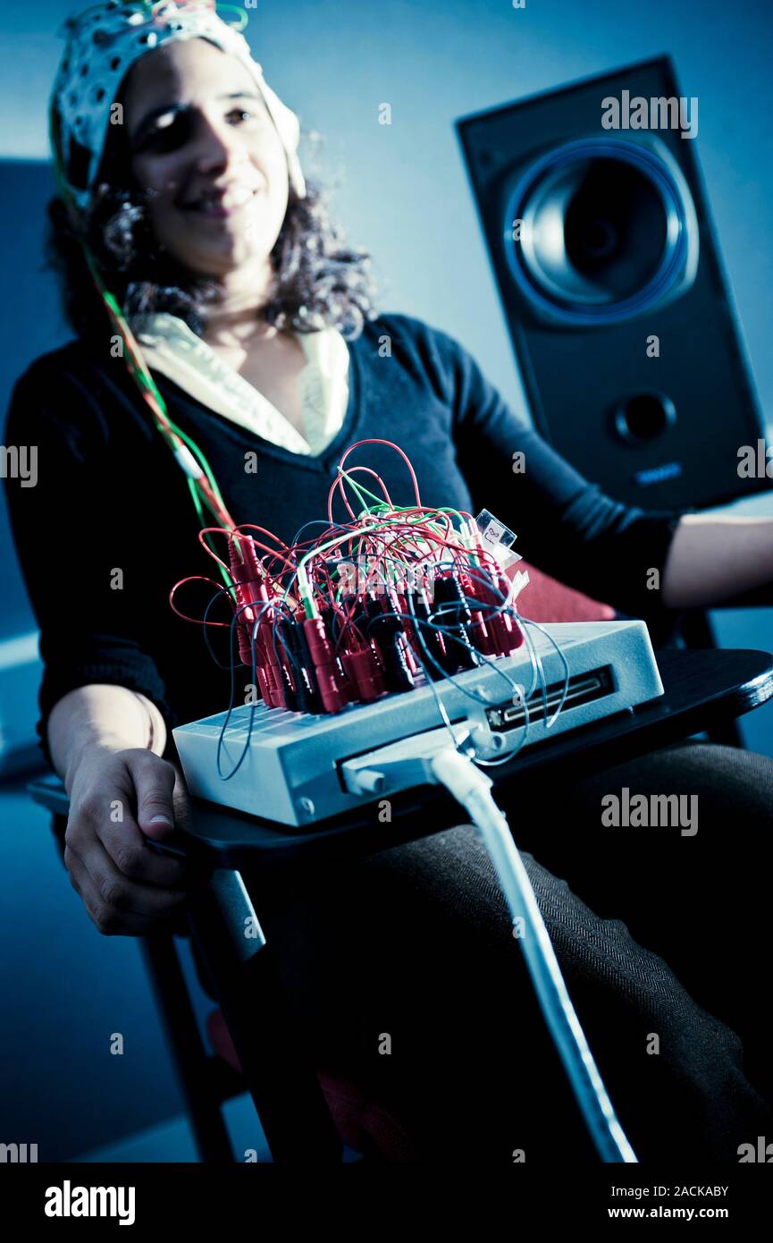 Woman in a sound booth wearing an electroencephalogram (EEG) cap to ...