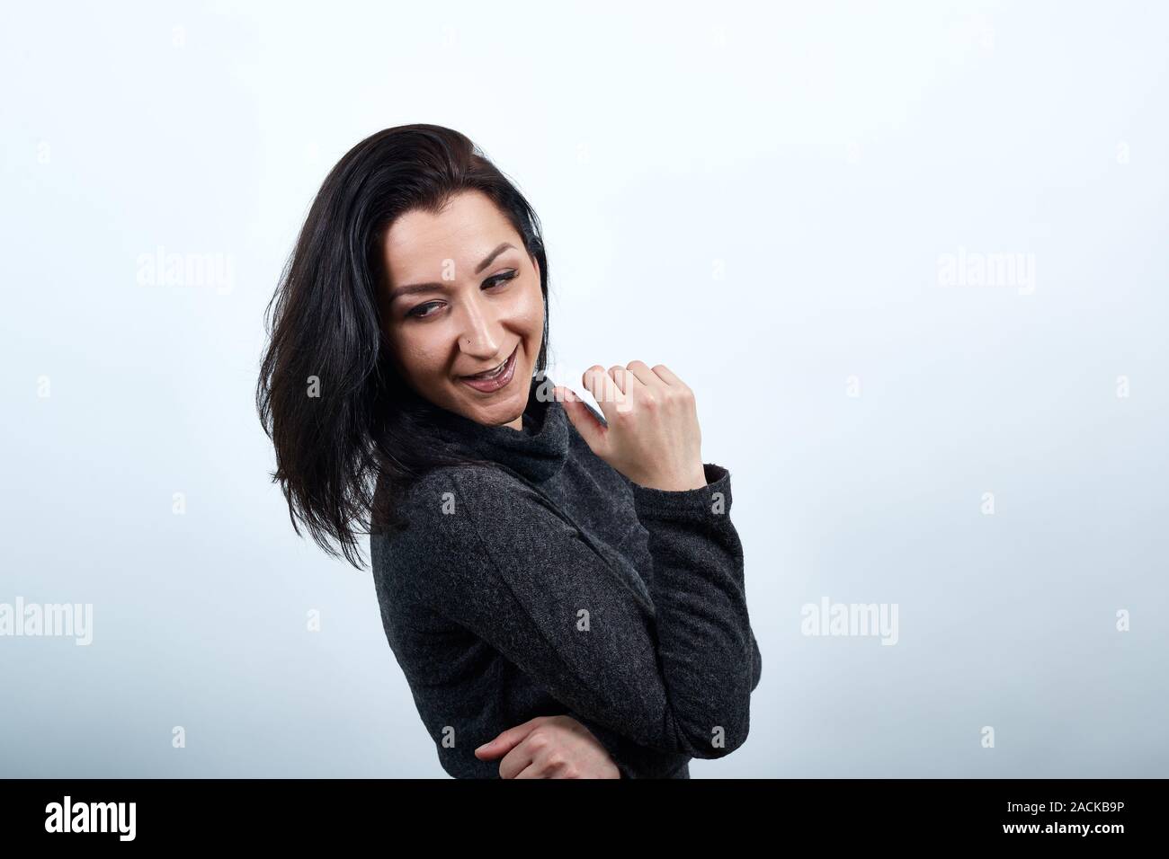 Caucasian lady staying sideways, keeping hand on stomach, smiling ...