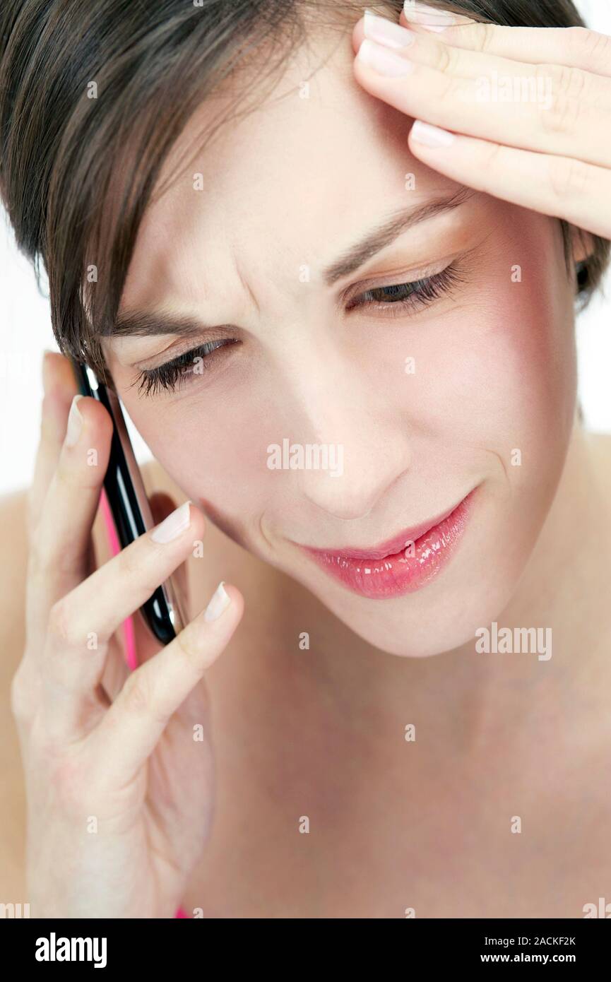 Mobile phone use. Woman using a mobile phone while looking concerned ...