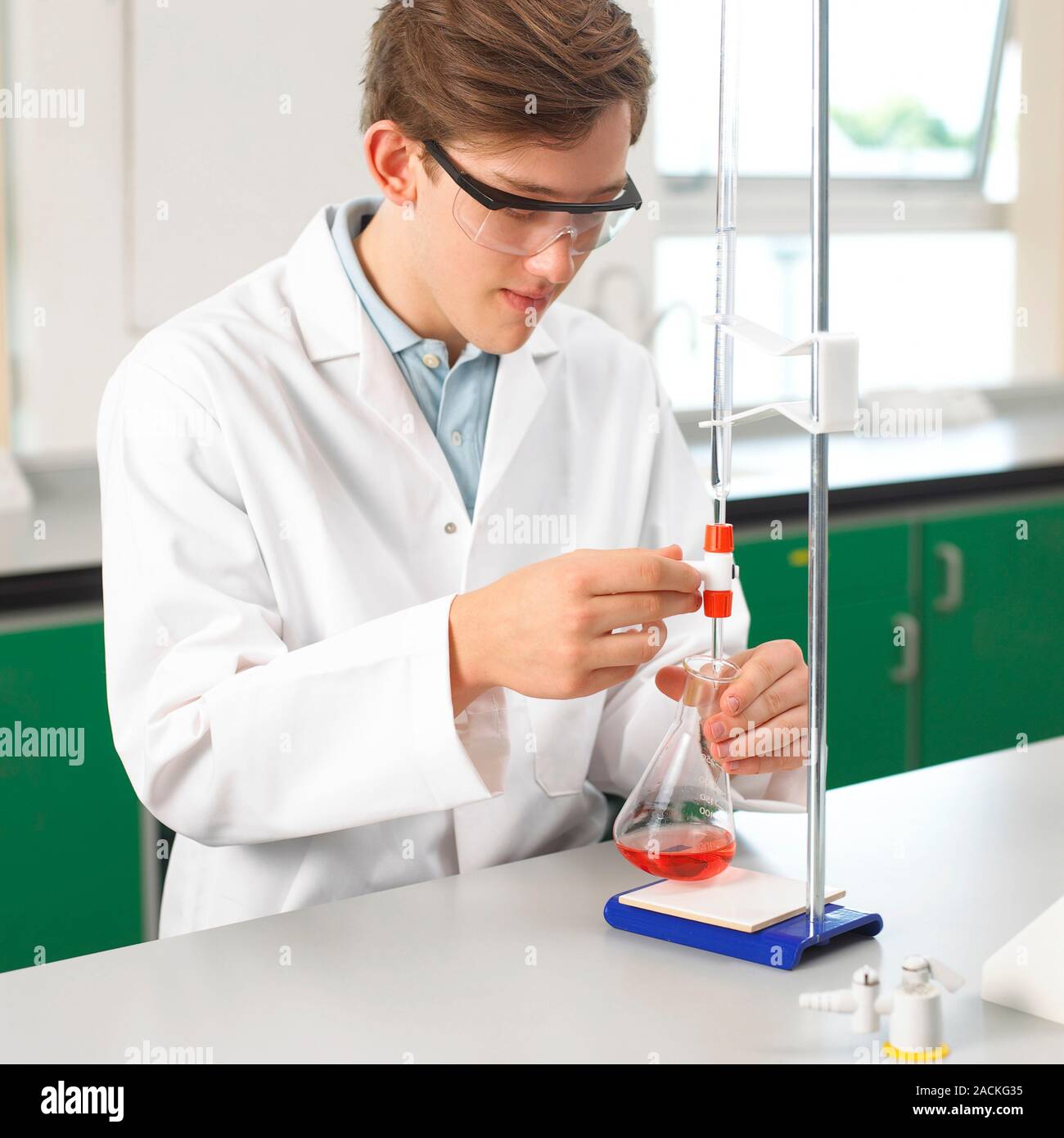 Titration experiment. Student using a burette and conical flask to ...