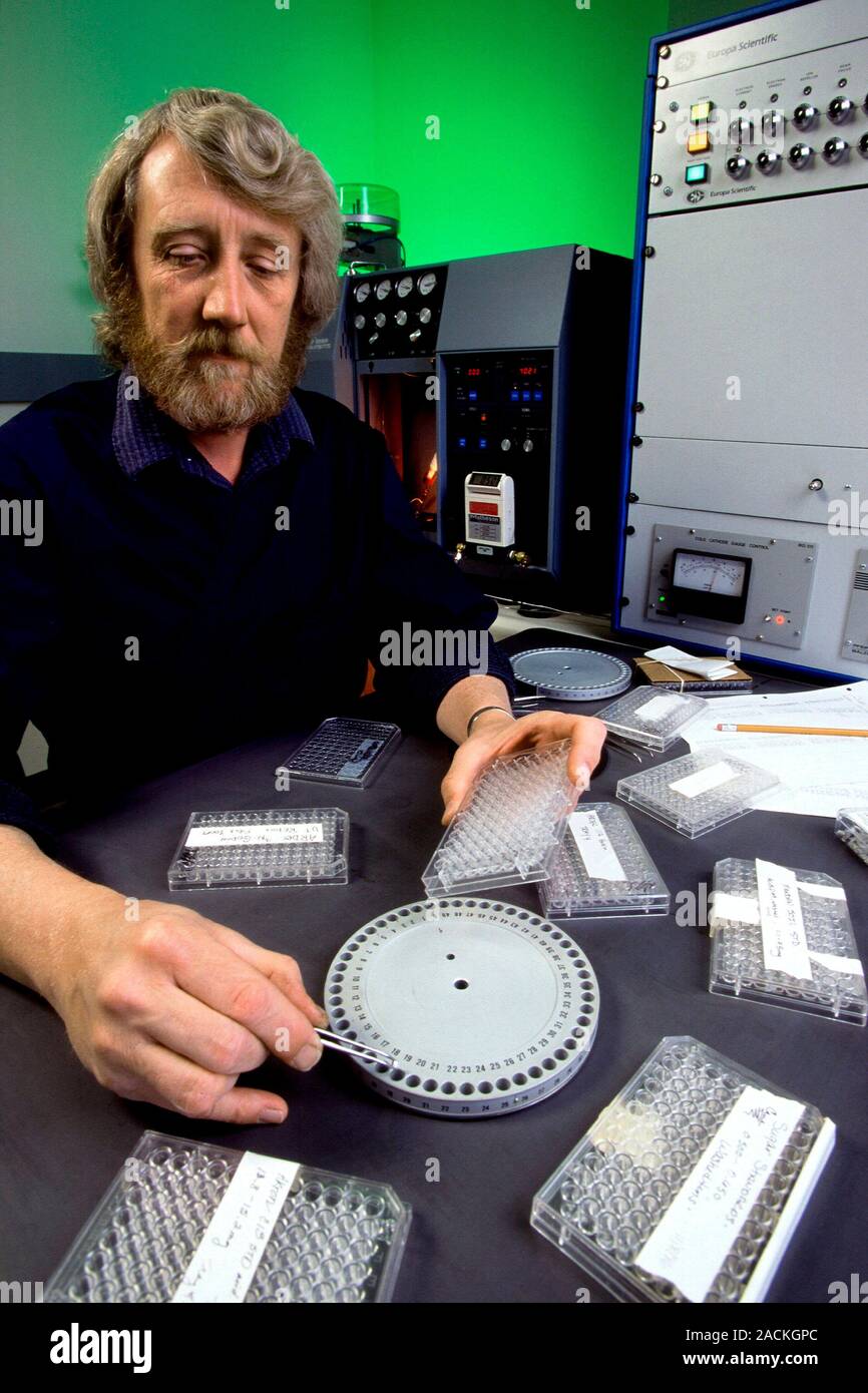 Plant carbon use research. Technician loading samples of soil into a ...