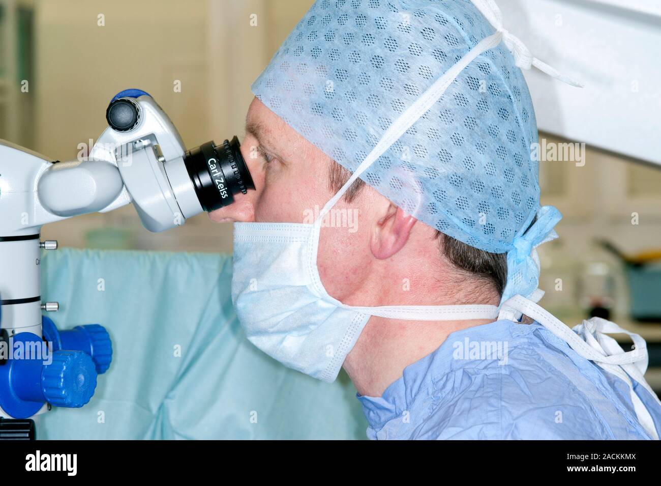 Surgeon conducts eye microsurgery using a microscope suspended over the ...