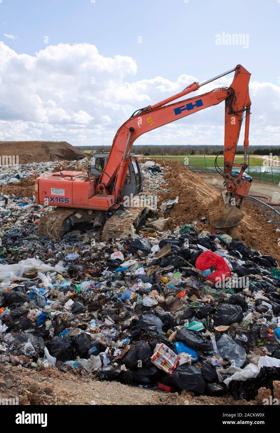 Landfill site. Digger covering waste at a landfill site with soil ...
